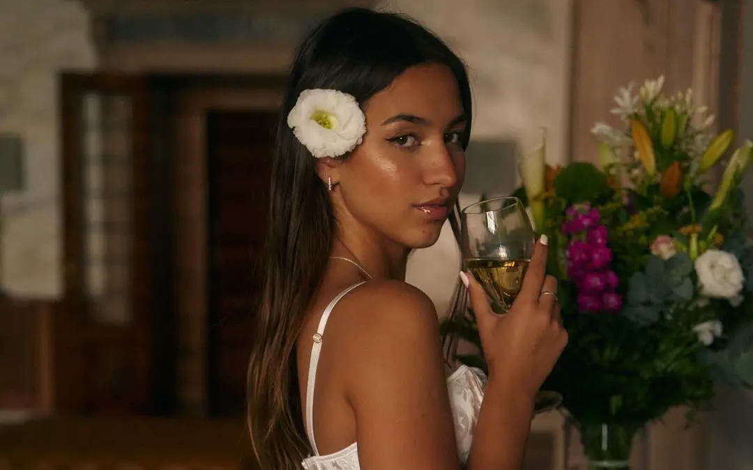 Mikaela Fuente en lencería blanca posando frente a un jarrón de flores - ColorMusic