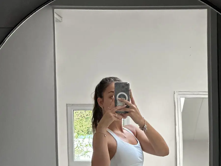 Mikaela Fuente tomándose una selfie en el espejo con un conjunto deportivo - ColorMusic